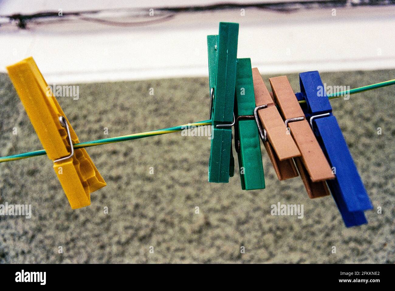 Closeup photo of some plastic cloth clips on a wire. Shot on Fujicolor ...