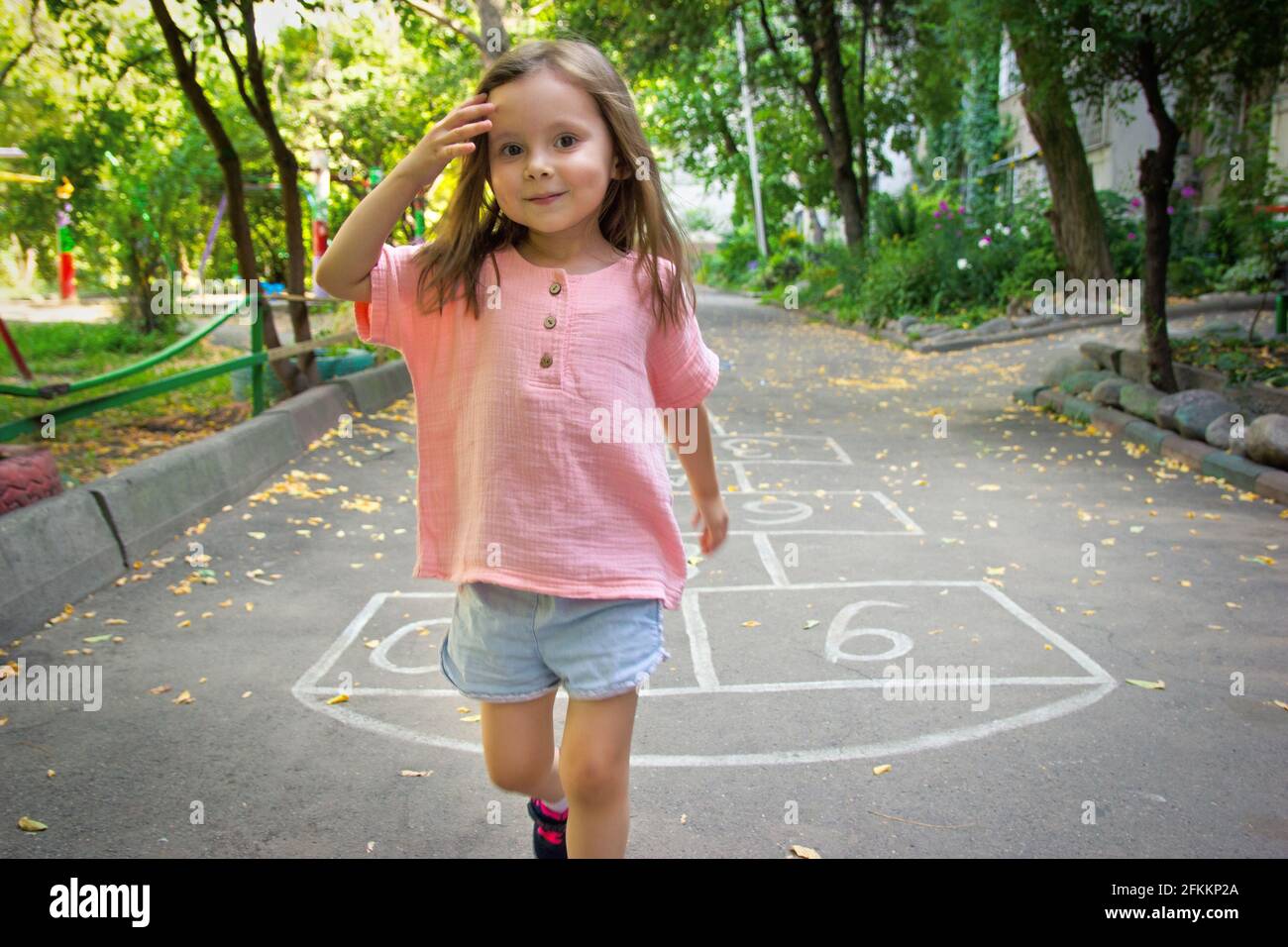 Little cute girl 4 y.o. playing hopscotch on playground outdoors ...