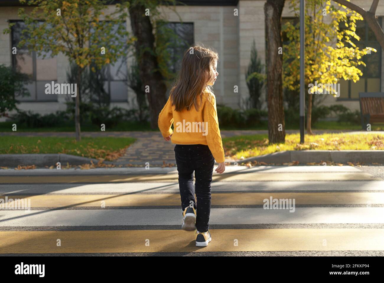 A little girl crosses the road on a zebra crossing, looks around Stock ...