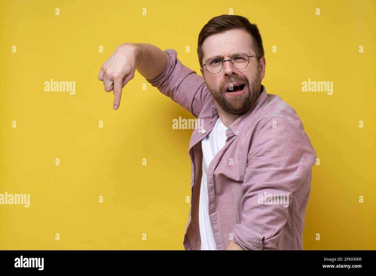 Bewildered man persistently points finger down and looks inquiringly at ...