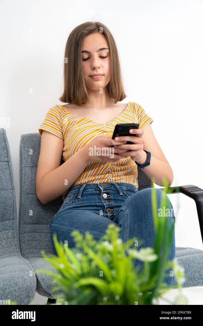 A young female client in the waiting room with a mask browsing on the ...