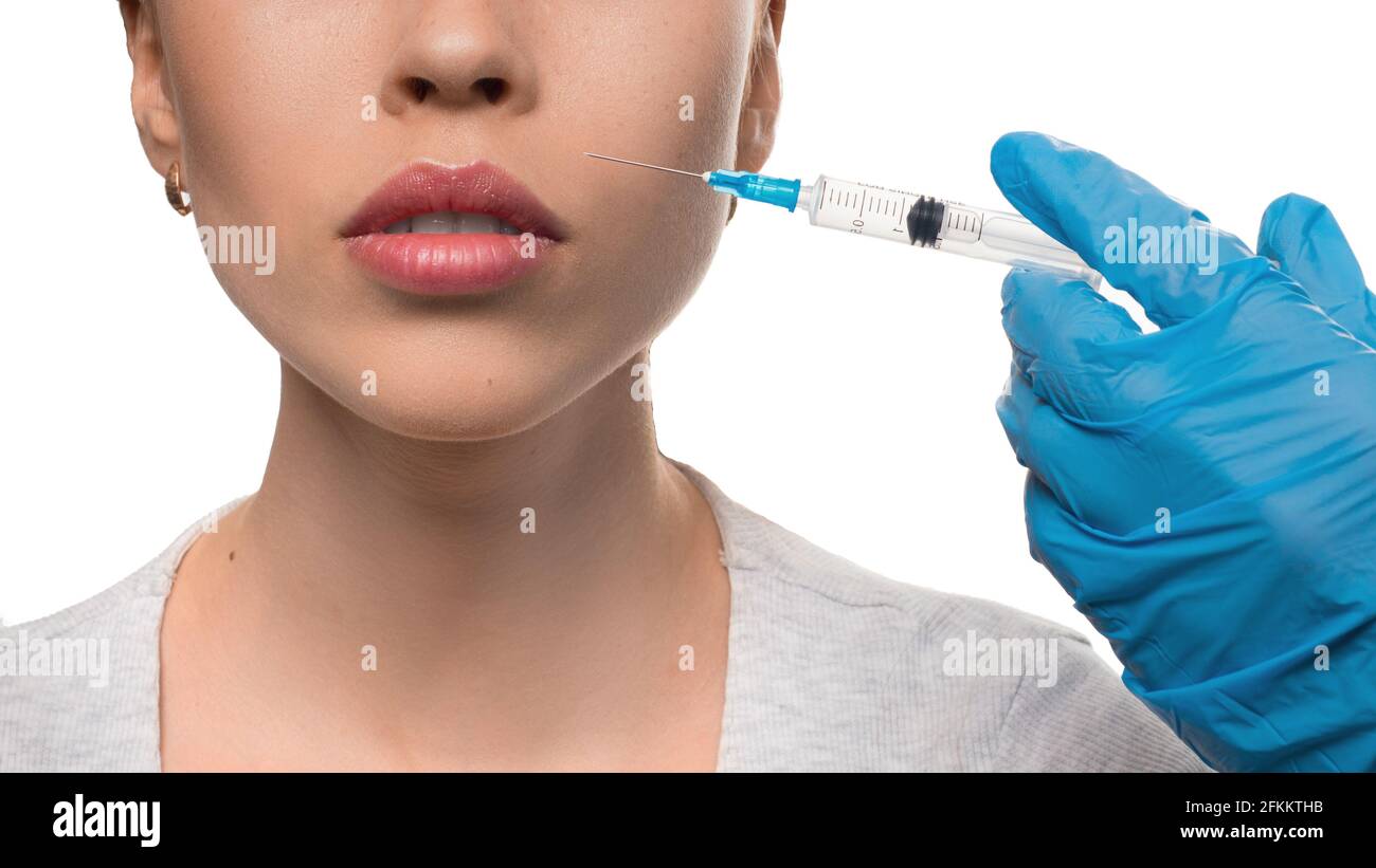 Beauty injections. Close-up view - gloved hands with a syringe inject ...