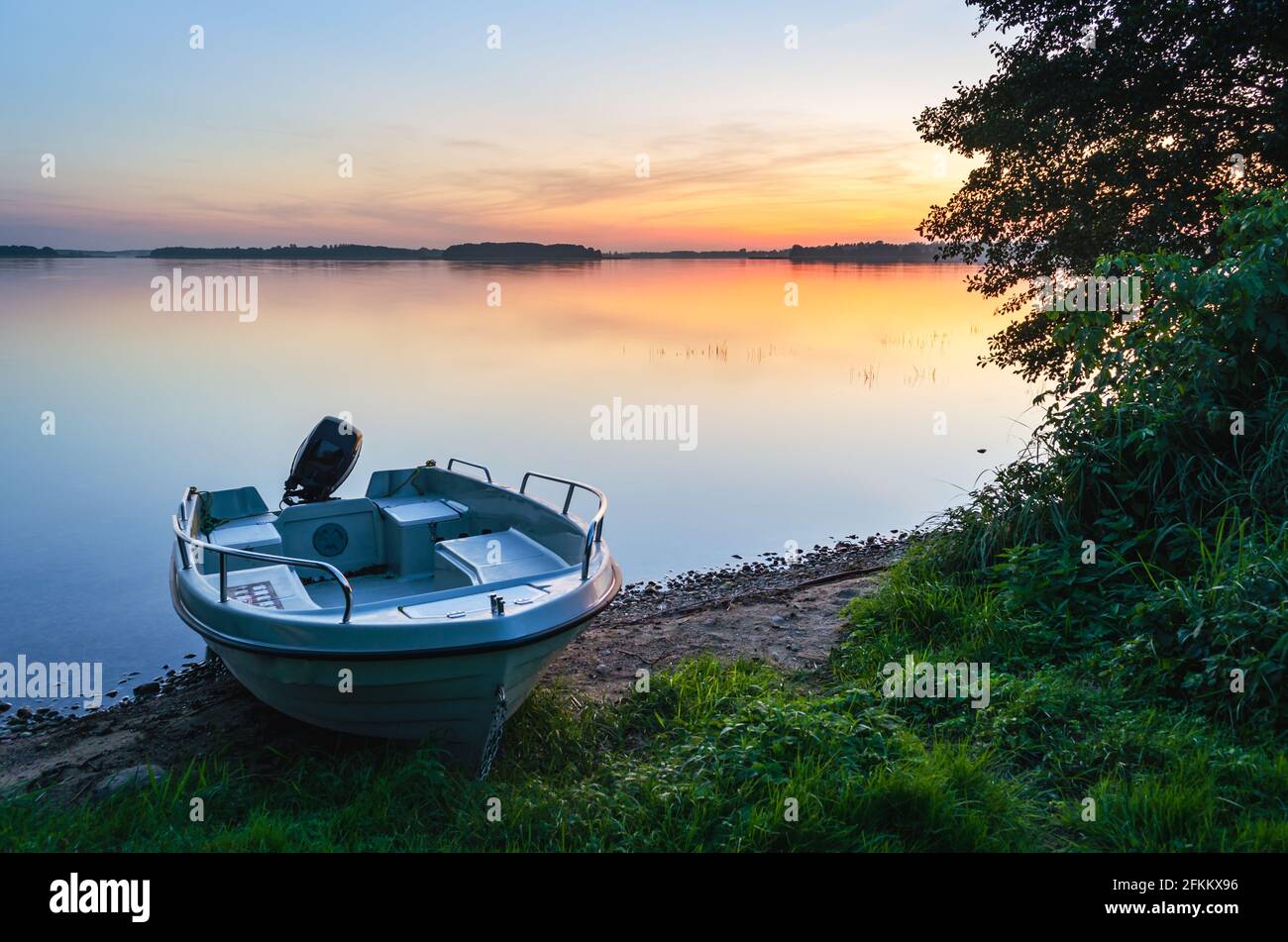 Masurian lake, sunset, motor boat on the lake shore Stock Photo - Alamy