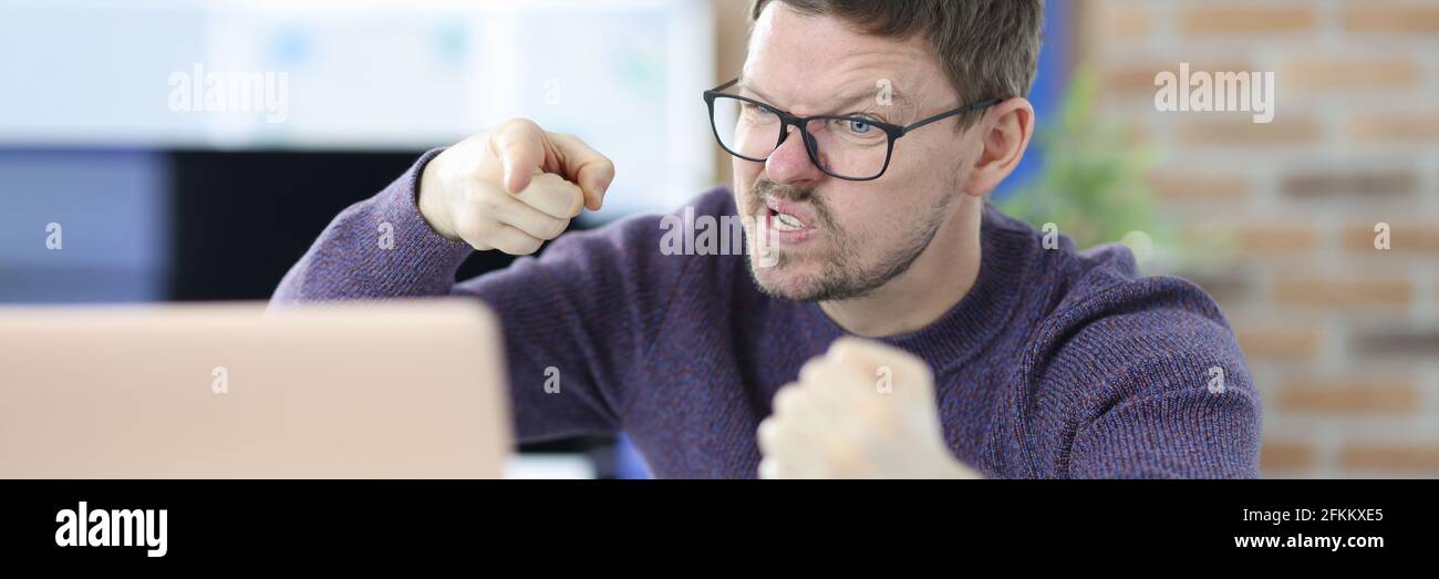 Angry man sits at work table in front of laptop Stock Photo - Alamy