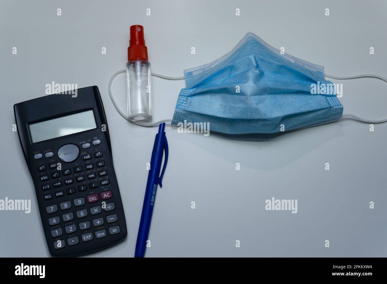A top view of calculator, pen, hand sanitizer and face mask on white ...