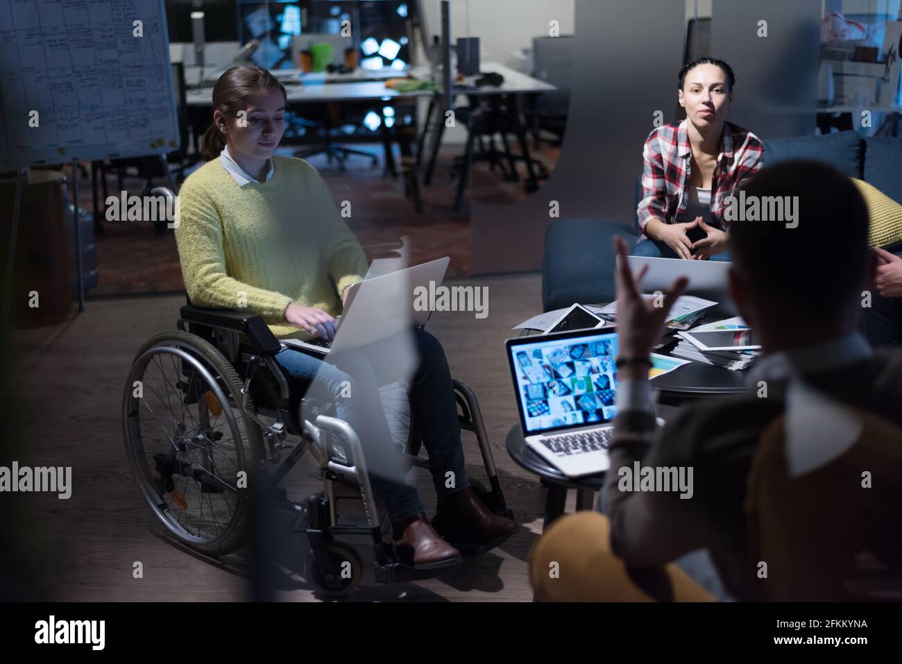 Office workers and handicaped person in a wheelchair discussing ...