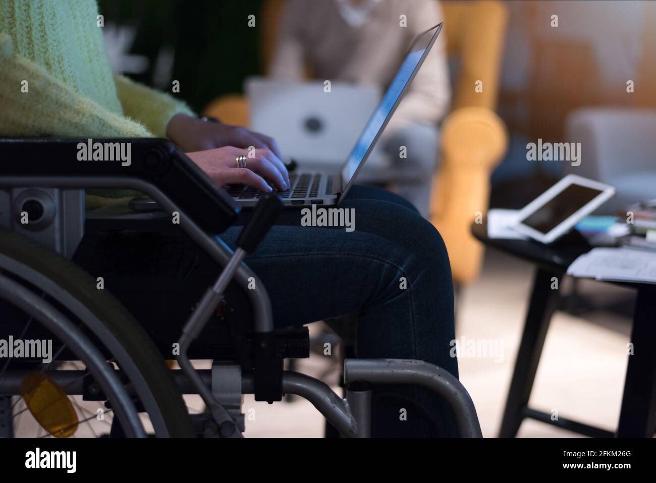 Young woman in wheelchair using computer laptop at modern workplace ...