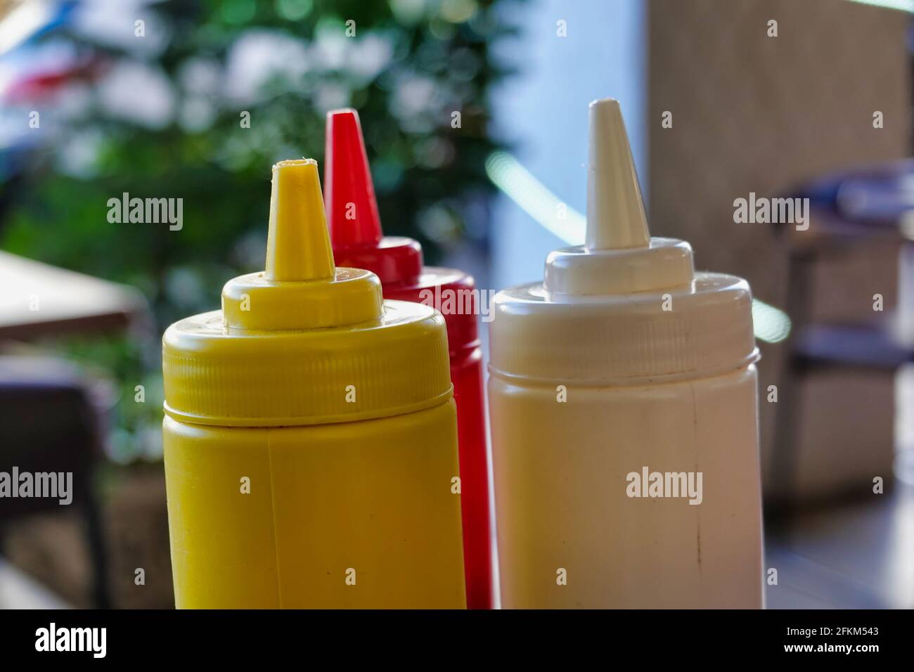 Three mustard, ketchup and mayonnaise containers on a blurred ...