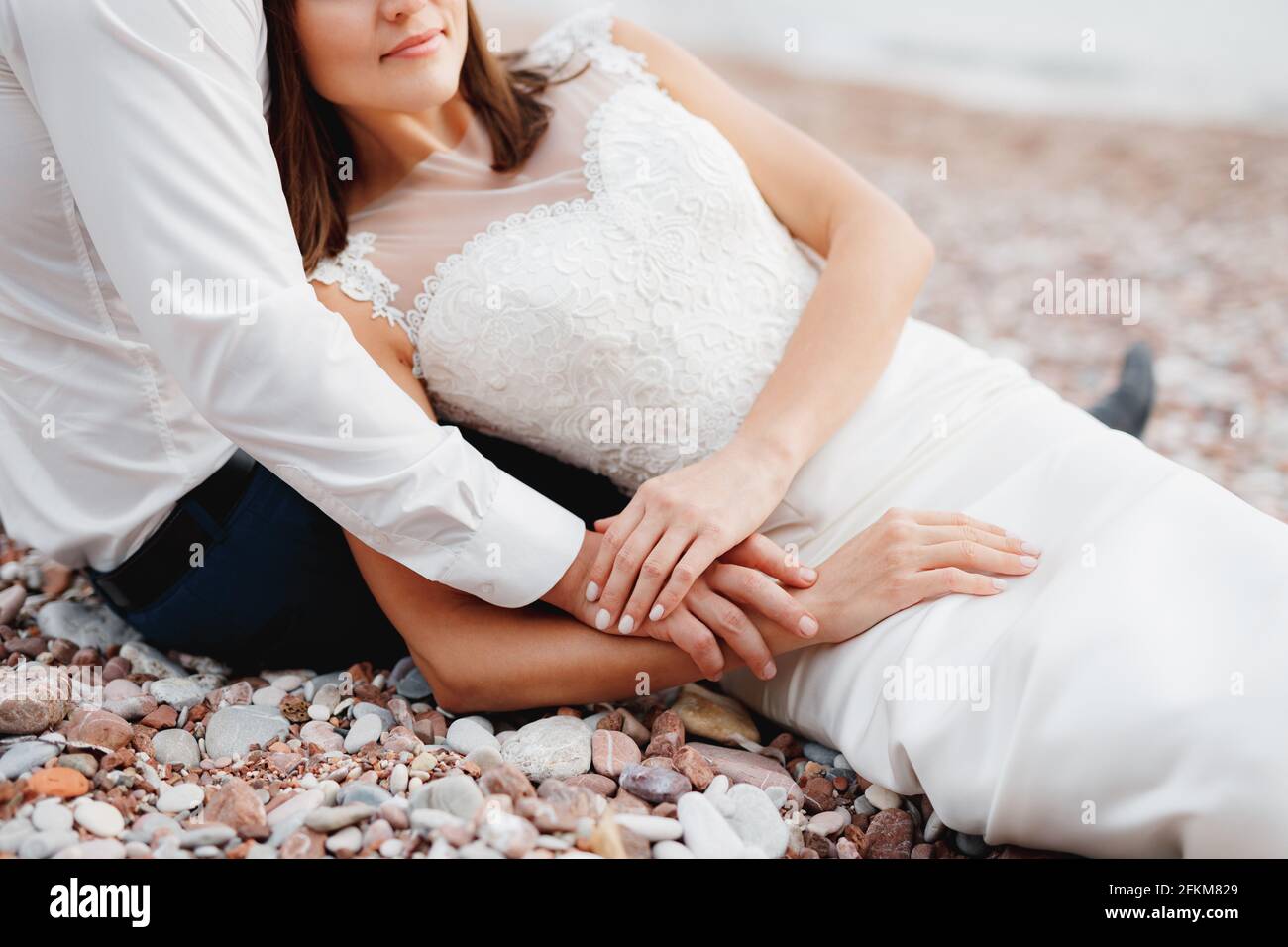 Groom in white shirt hugs the bride lying in a white lace dress Stock ...