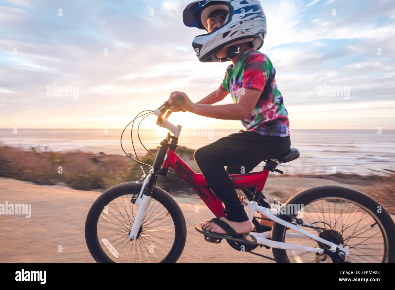Young boy riding his bike on a coastal trail at sunset Stock Photo - Alamy