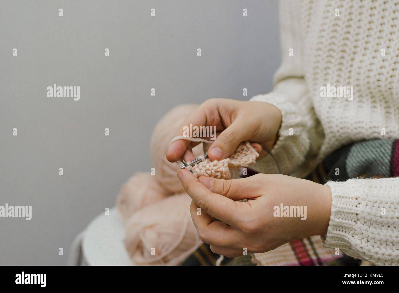 Women's hands knit from flesh-colored yarn, gray background Stock Photo ...