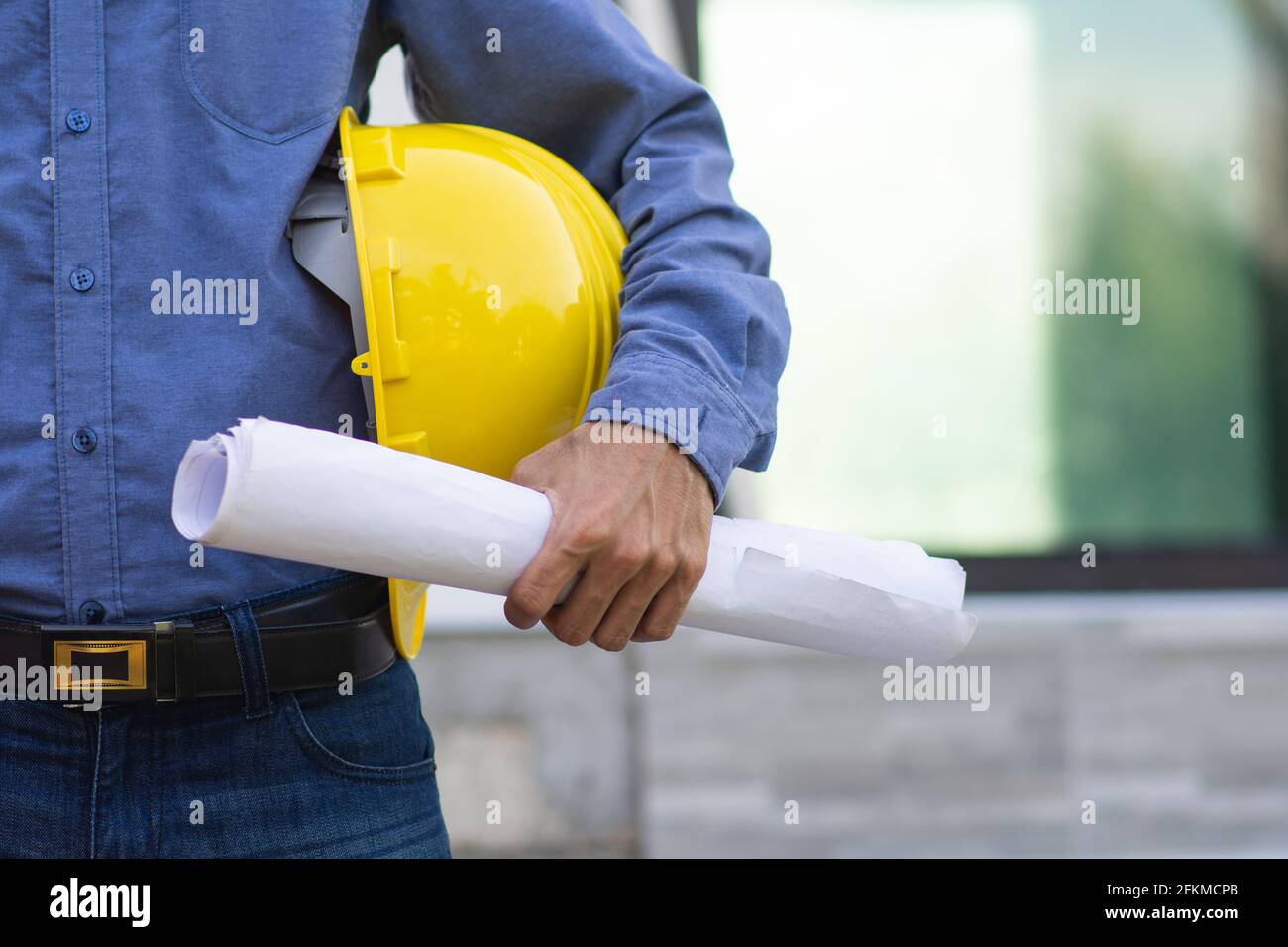 Engineer holding blueprint with yellow hard hat on site construction ...