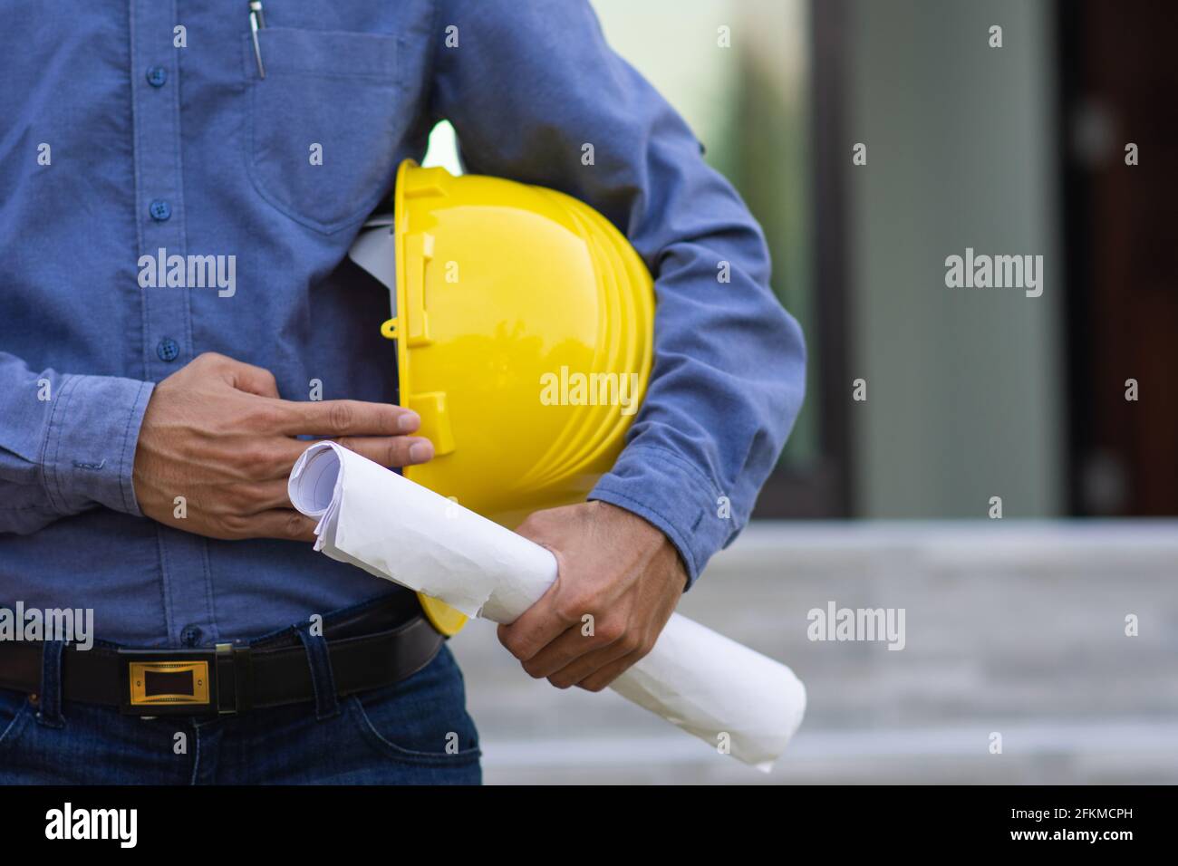 Engineer holding blueprint with yellow hard hat on site construction ...