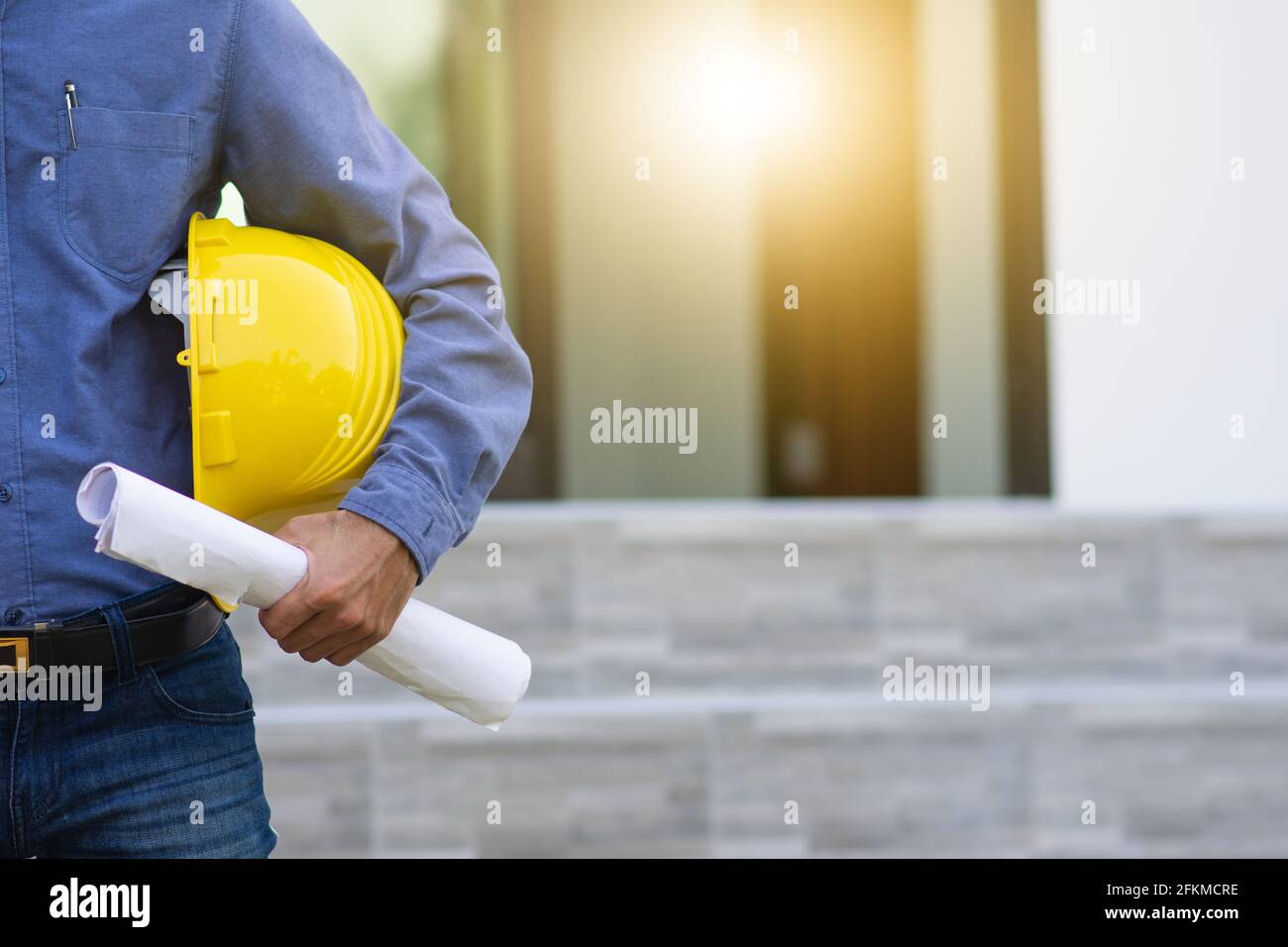 Engineer holding blueprint with yellow hard hat on site construction ...