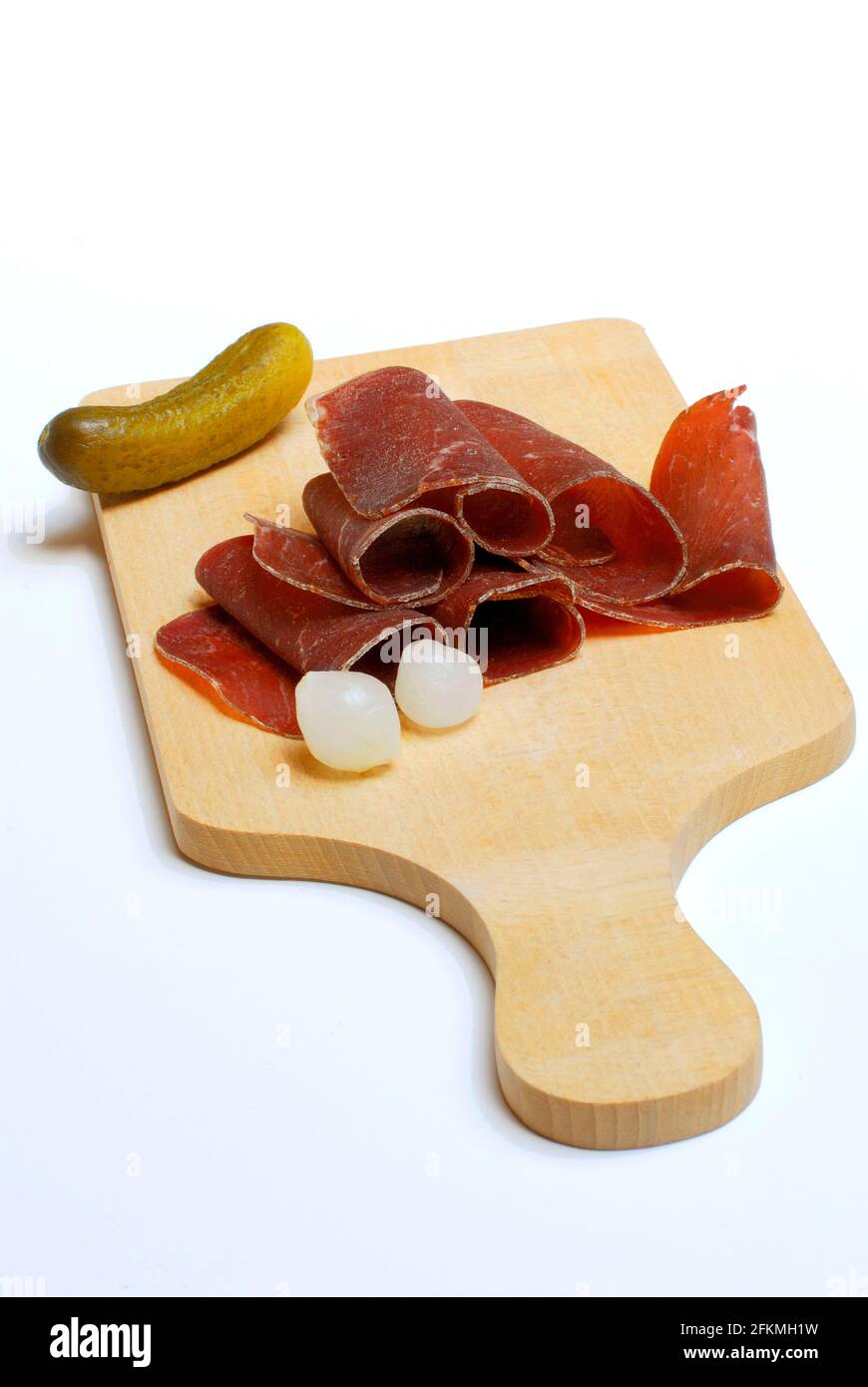 Buendner dried meat on wooden board, with delicacy gherkin and silver ...