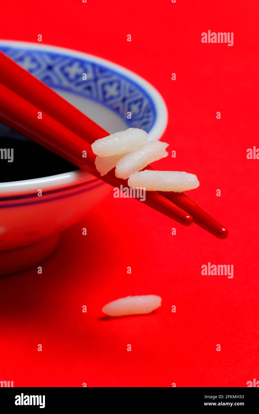 Rice grains on chopsticks, bowl with soy sauce, chopsticks, rice Stock ...