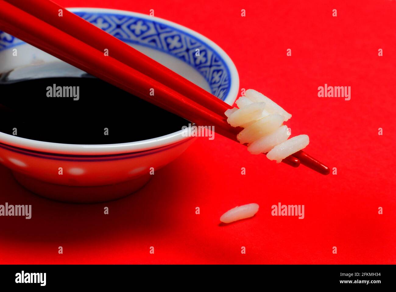 Rice grains on chopsticks, bowl with soy sauce, chopsticks, rice Stock ...