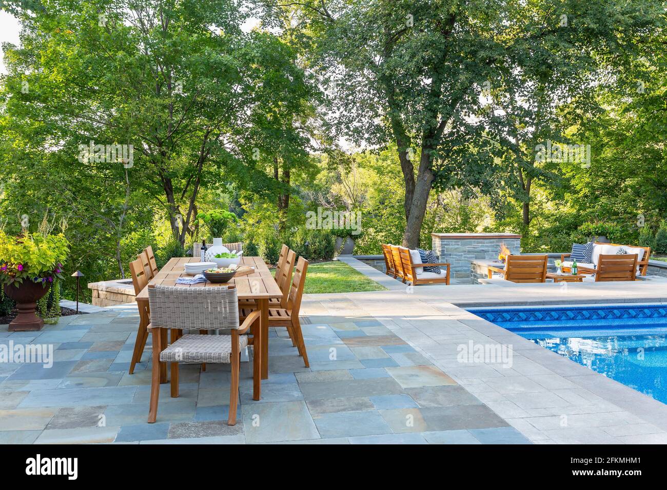Dining table on patio next to swimming pool and sunken firepit Stock ...