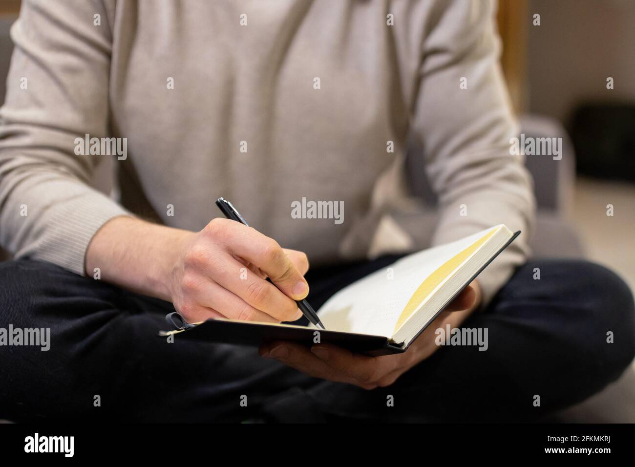 Young bearded man writes in a diary while working from home. Remote job ...