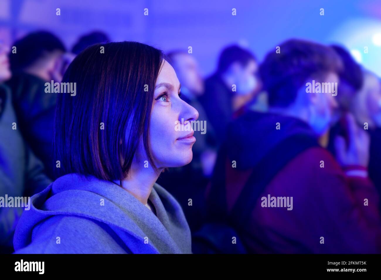 Girl standing at concert on background of people crowd and neon light ...