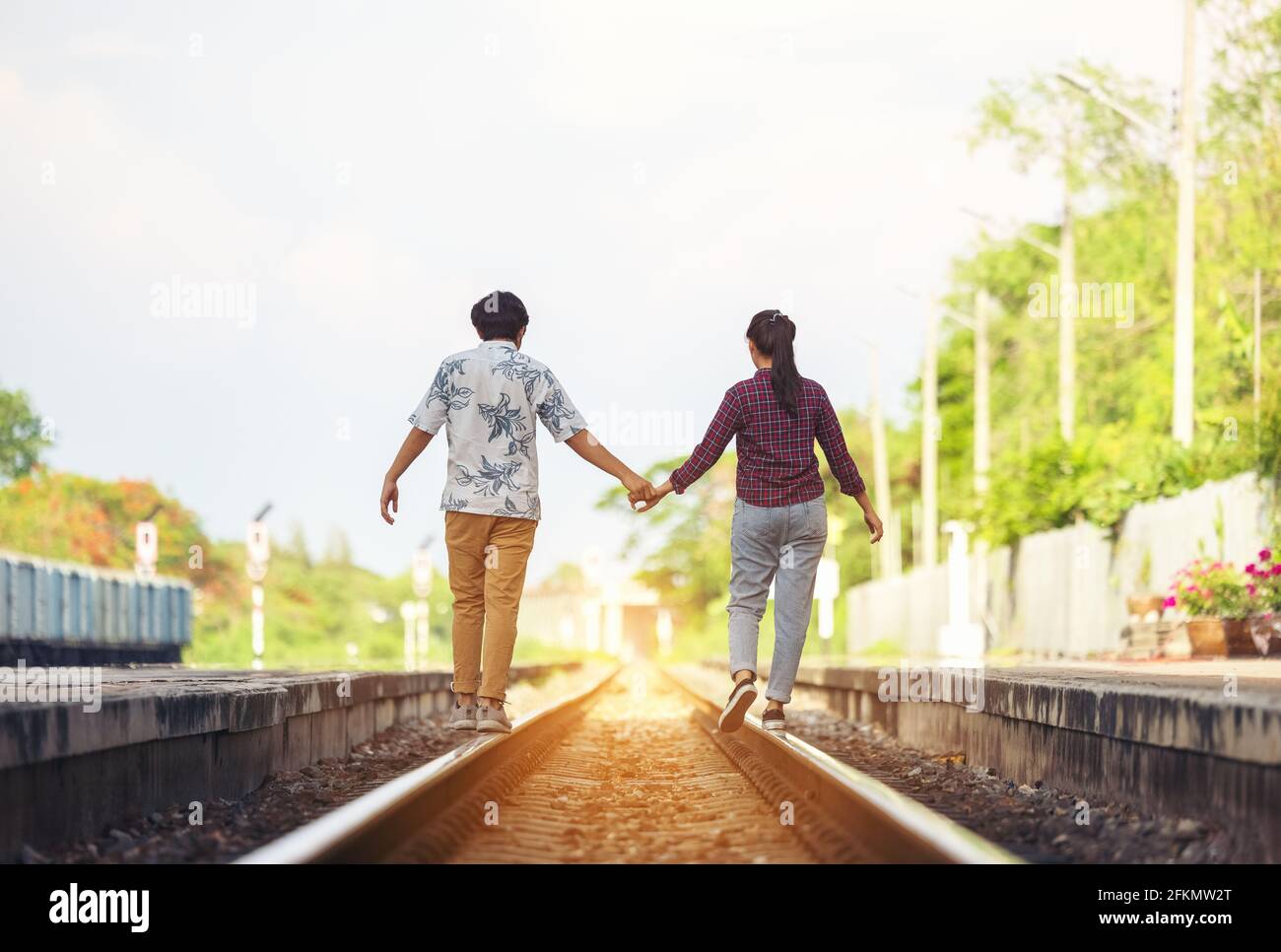 Young couple walking hand in hand on railway tracks, along railroad ...