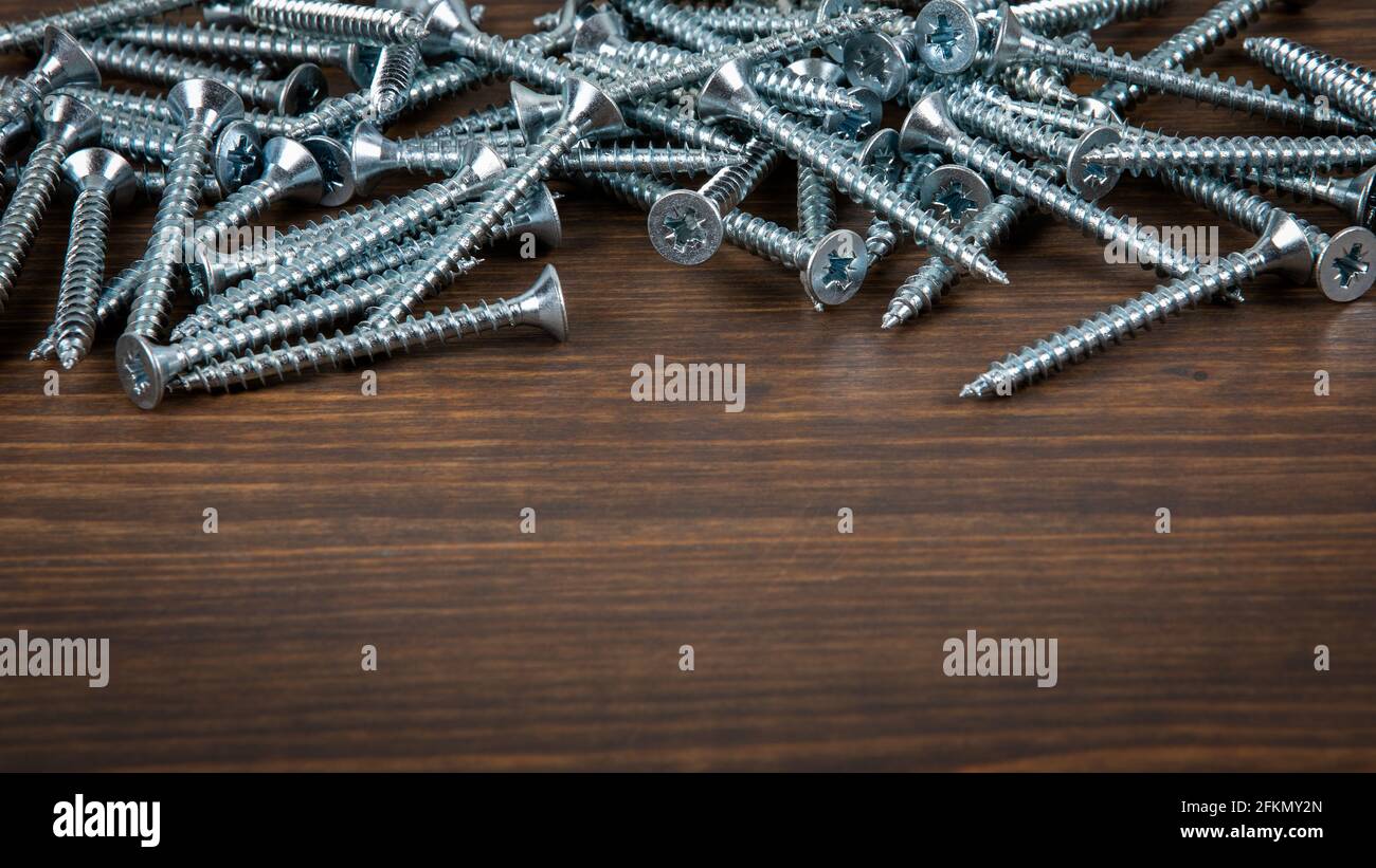 Galvanized screws on a wooden background. Construction and repair Stock ...