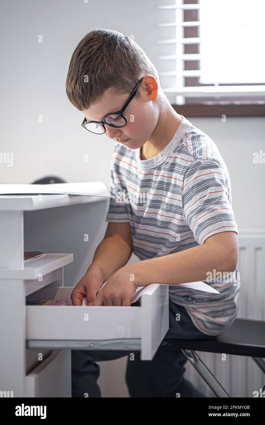 Little boy with glasses sitting at his desk in front of a laptop ...