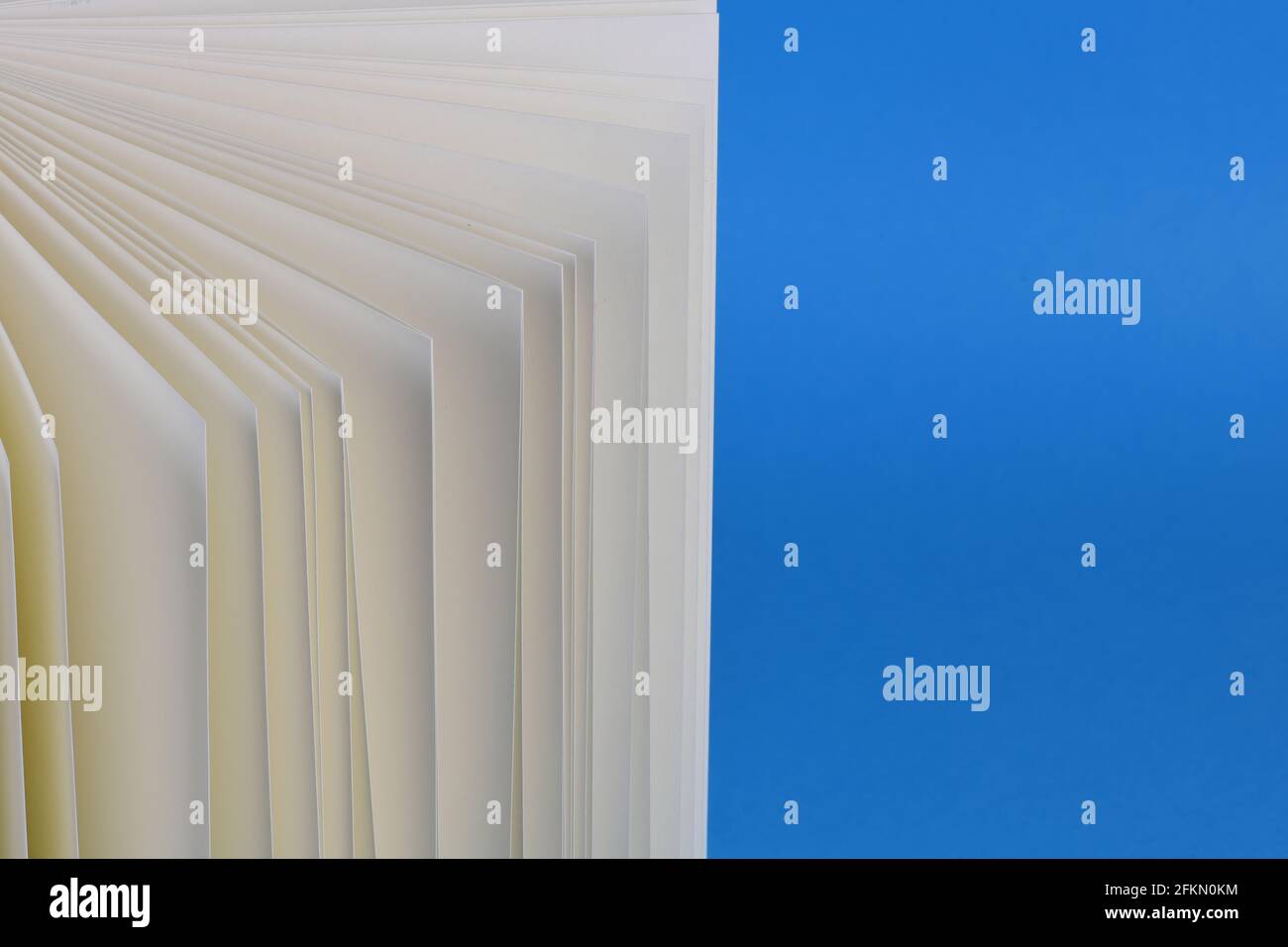Fan unfold open small notepad with blank light pages. Blue background ...
