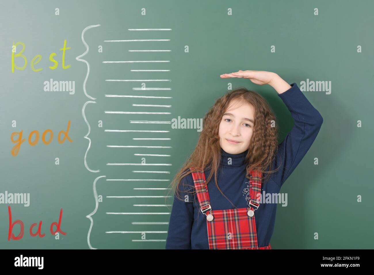 Pre-adolescent girl measuring her height on drawn chalk height meter ...
