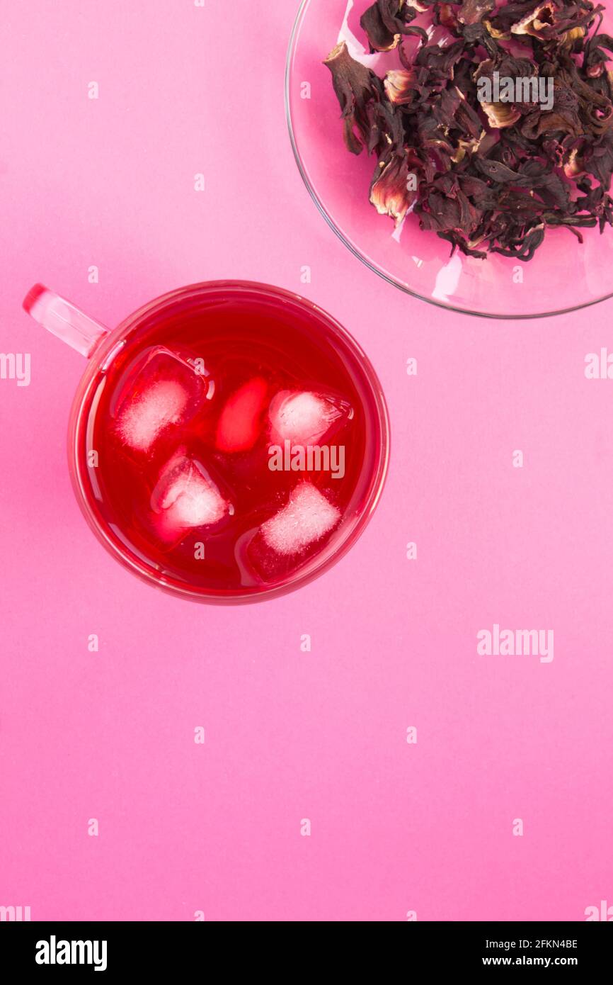 Iced hibiscus or karkade tea in the glass on the pink background ...