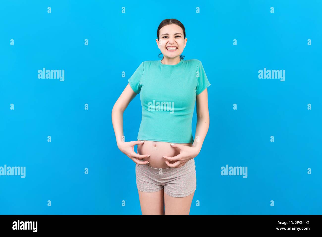 Pregnant woman scratching her belly on colored background Stock Photo ...