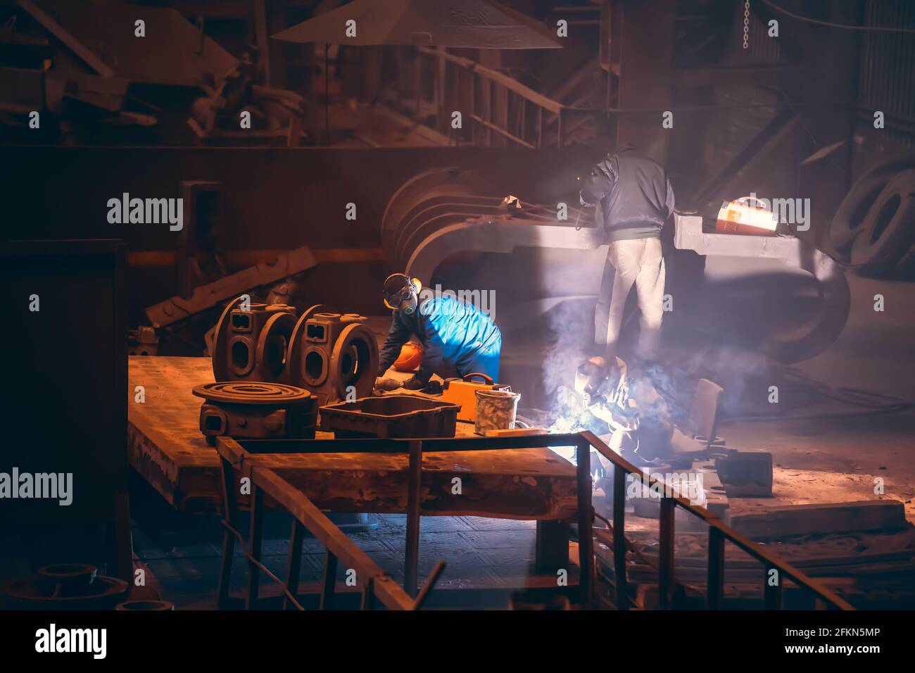 Worker welding metal parts at metallurgical plant, processing metal ...