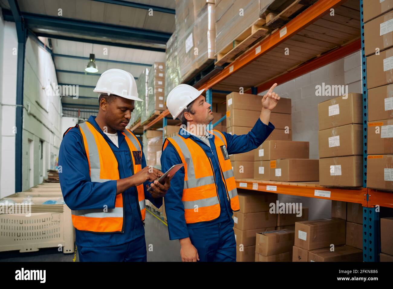 Two multiracial male workers working together in a manufacturing plant ...
