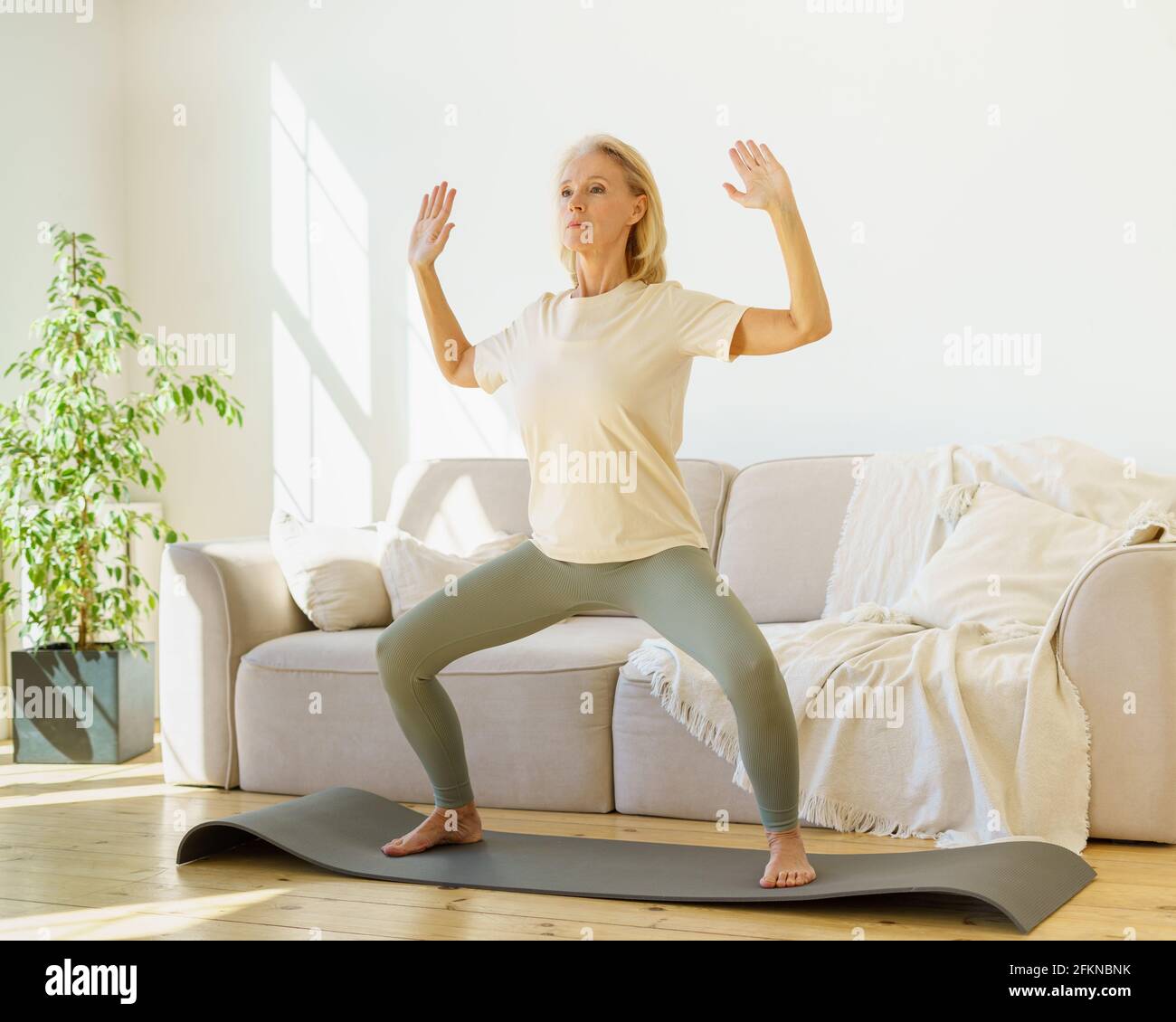 Active mature woman in sportswear standing in yoga asana or body ...