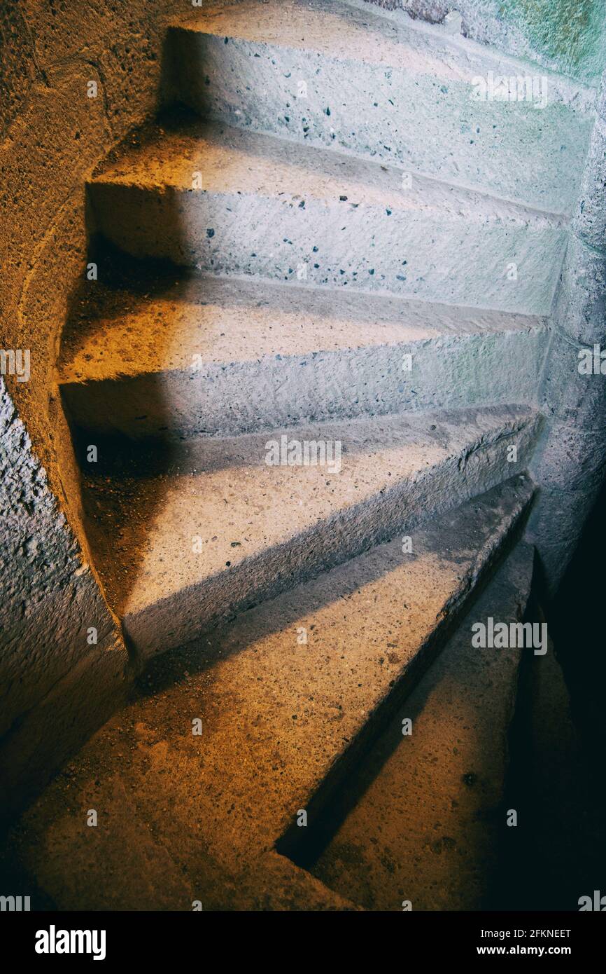 view of a spiral staircase made of old stone without railing and narrow ...