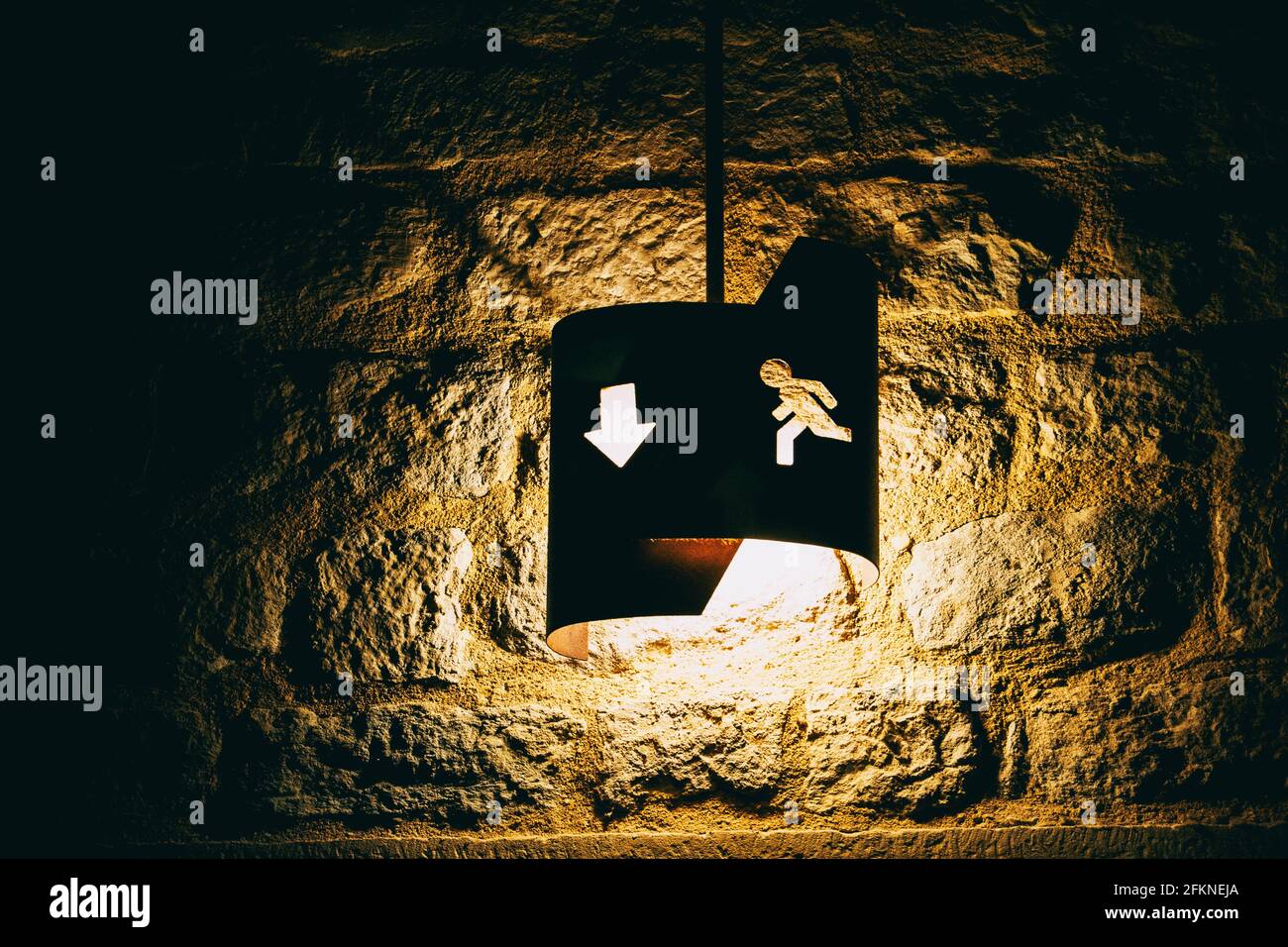 old fashioned emergency exit icon with backlit arrow on stone wall ...