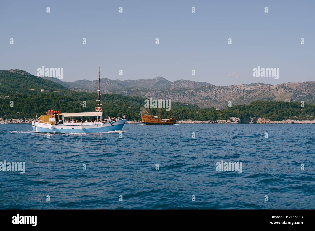 Blue and brown pleasure ships sail on the water against the background ...