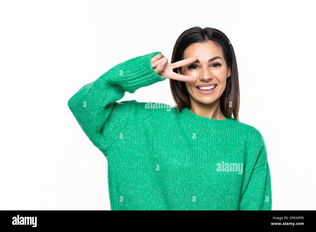 Beautiful young woman showing peace victory sign on white background ...