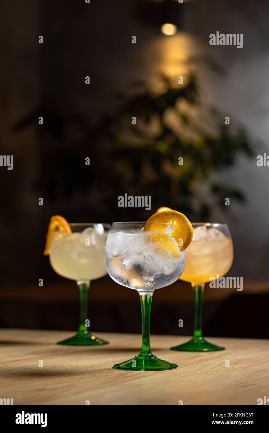 Gin and tonic alcohol drink with orange and ice on wooden bar table ...