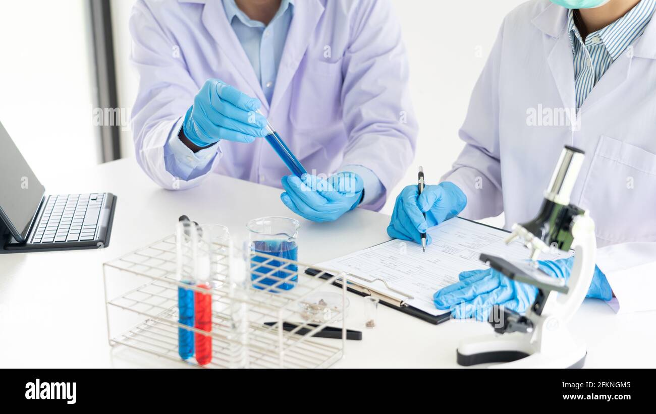 Attractive young scientist team in lab coat and safety goggles working ...