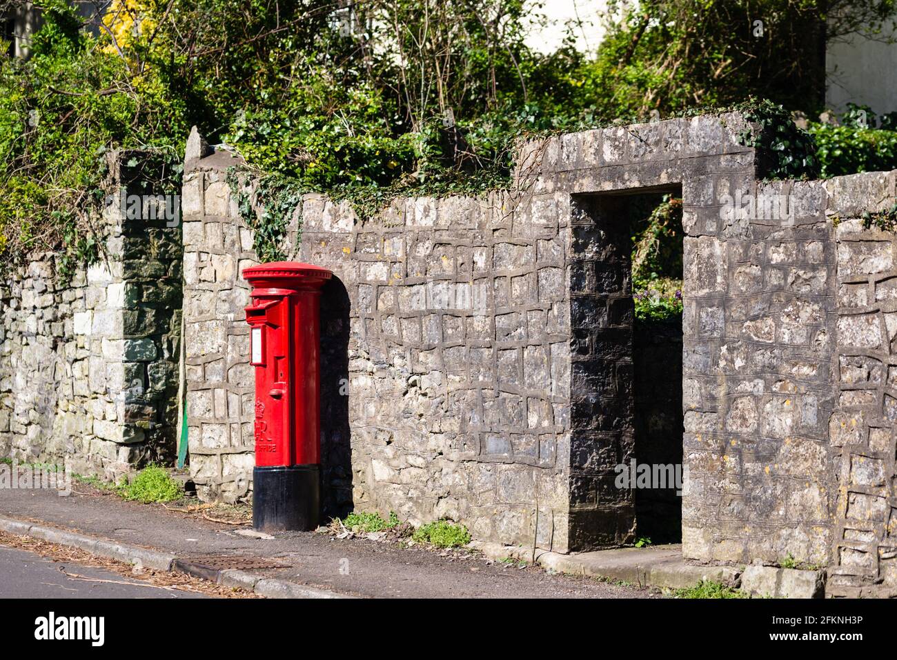 Red post box against a stone wall with an open entrance Stock Photo - Alamy