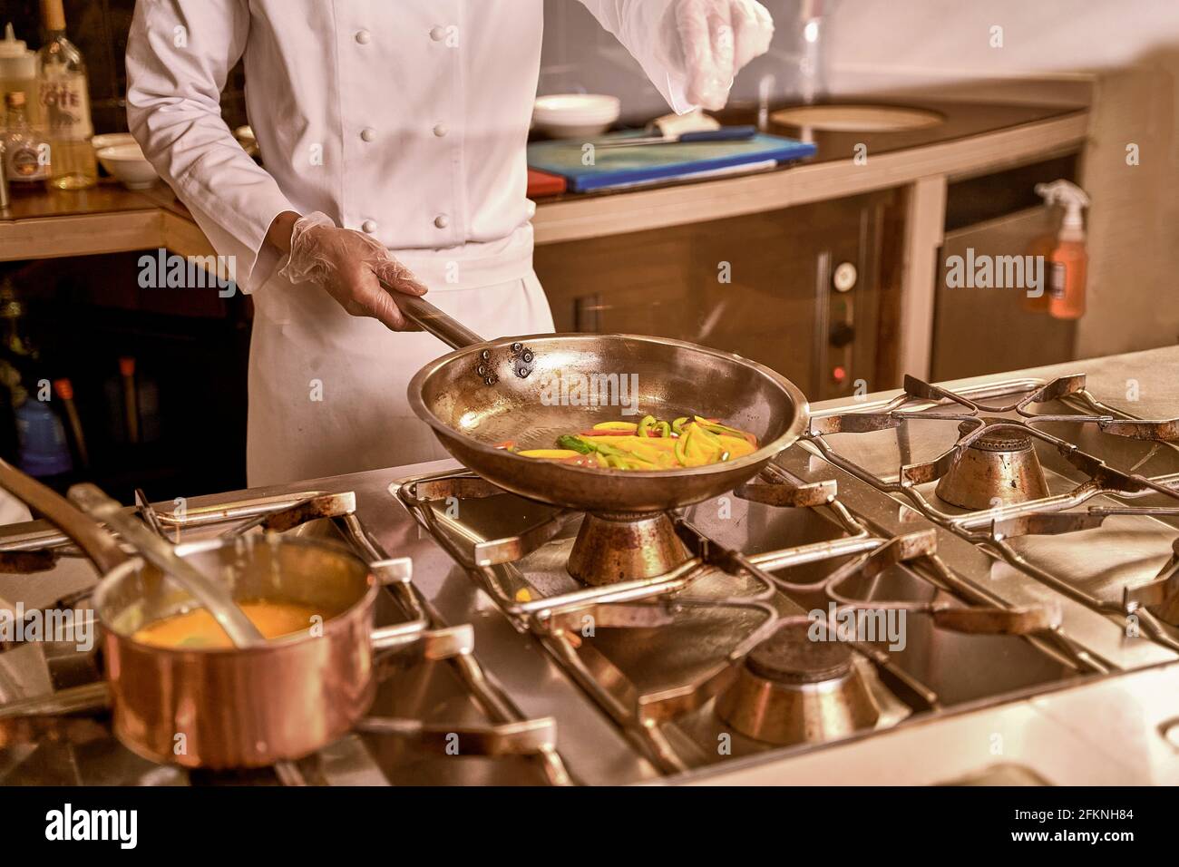 Cook adding salt to a frying pan with vegetables Stock Photo - Alamy