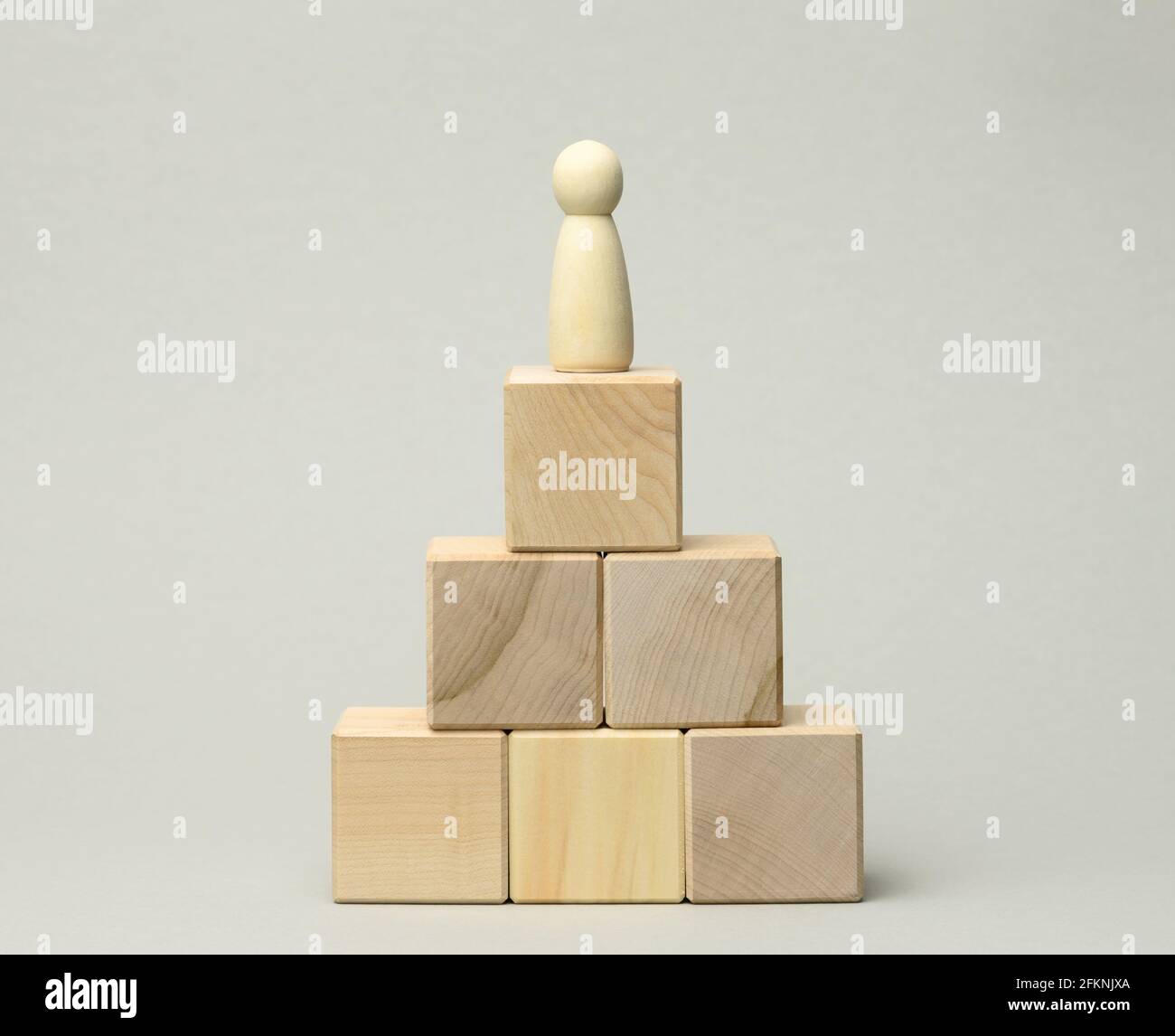 wooden figurine of a man at the top of the pyramid. The concept of ...