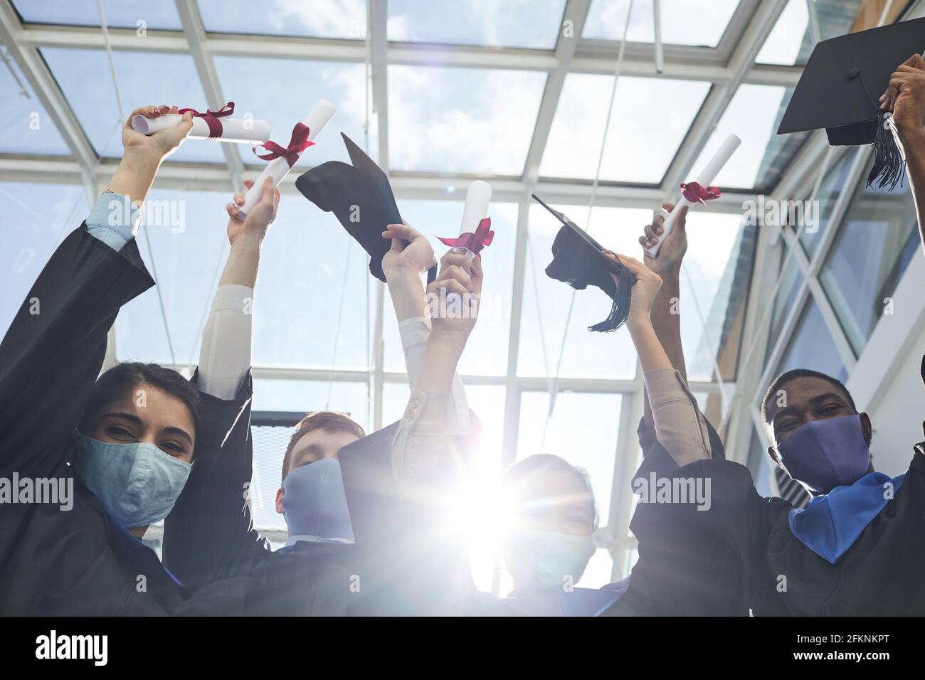 High angle view at group of university graduates holding diplomas up ...