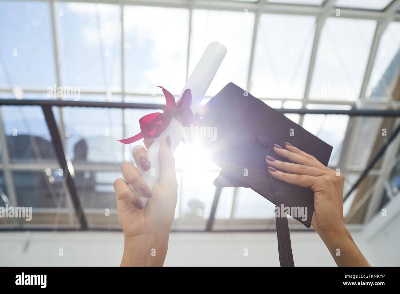 Close up of female hands holding graduation cap and diploma in sunlight ...
