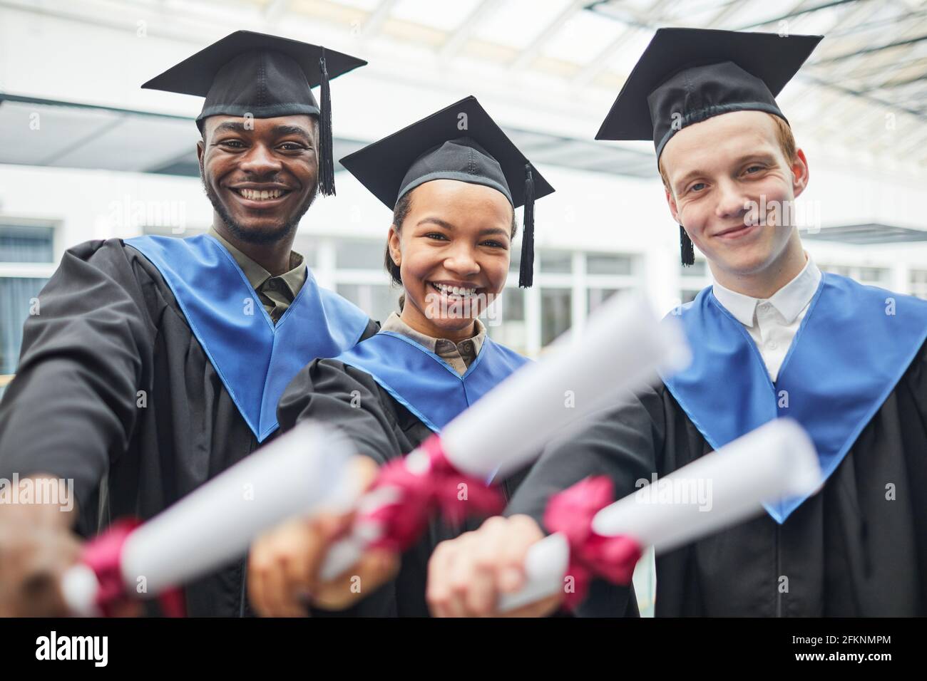Diverse group of college graduates holding diploma certificates and ...