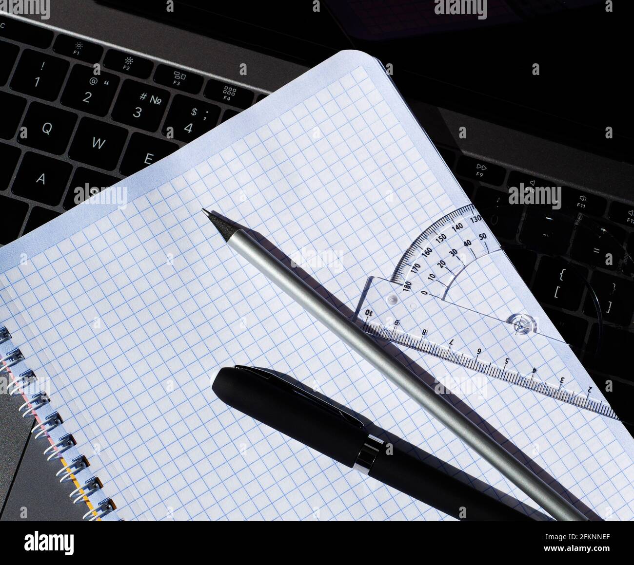 Notebook in a cage pencil ballpoint pen and protractor on the laptop ...