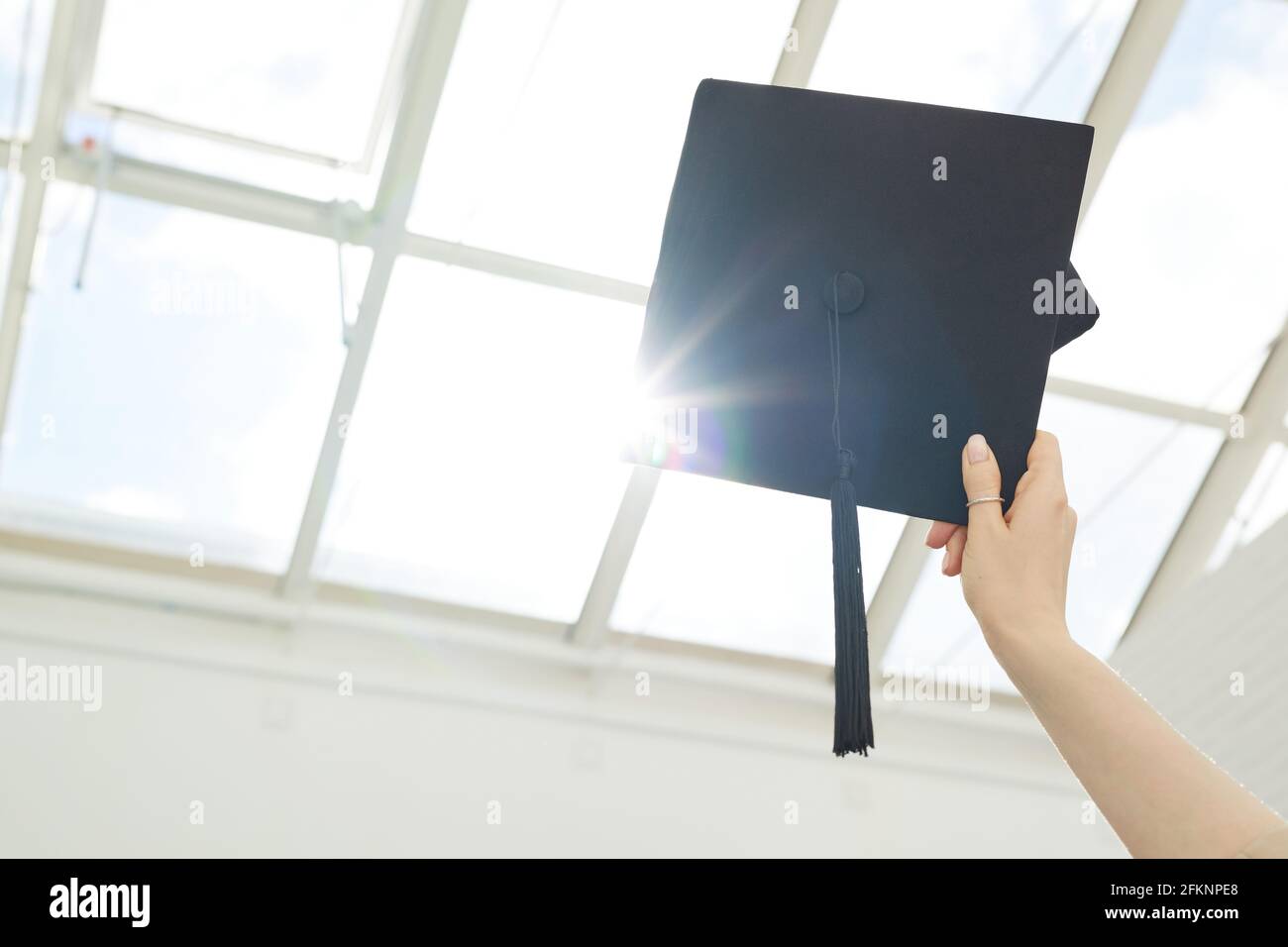 Close up of female hand holding graduation cap against sky background ...