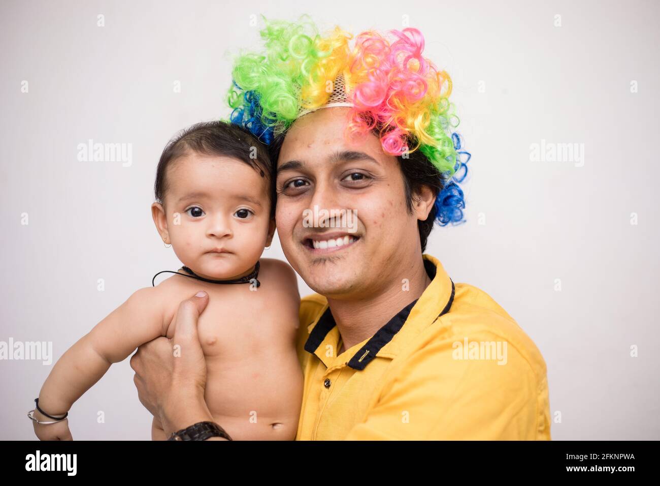 Indian smiling father with clown hat hugging his baby daughter Stock ...