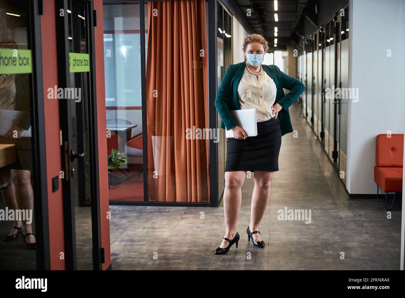 Self-assured personal assistant looking to camera in office corridor ...